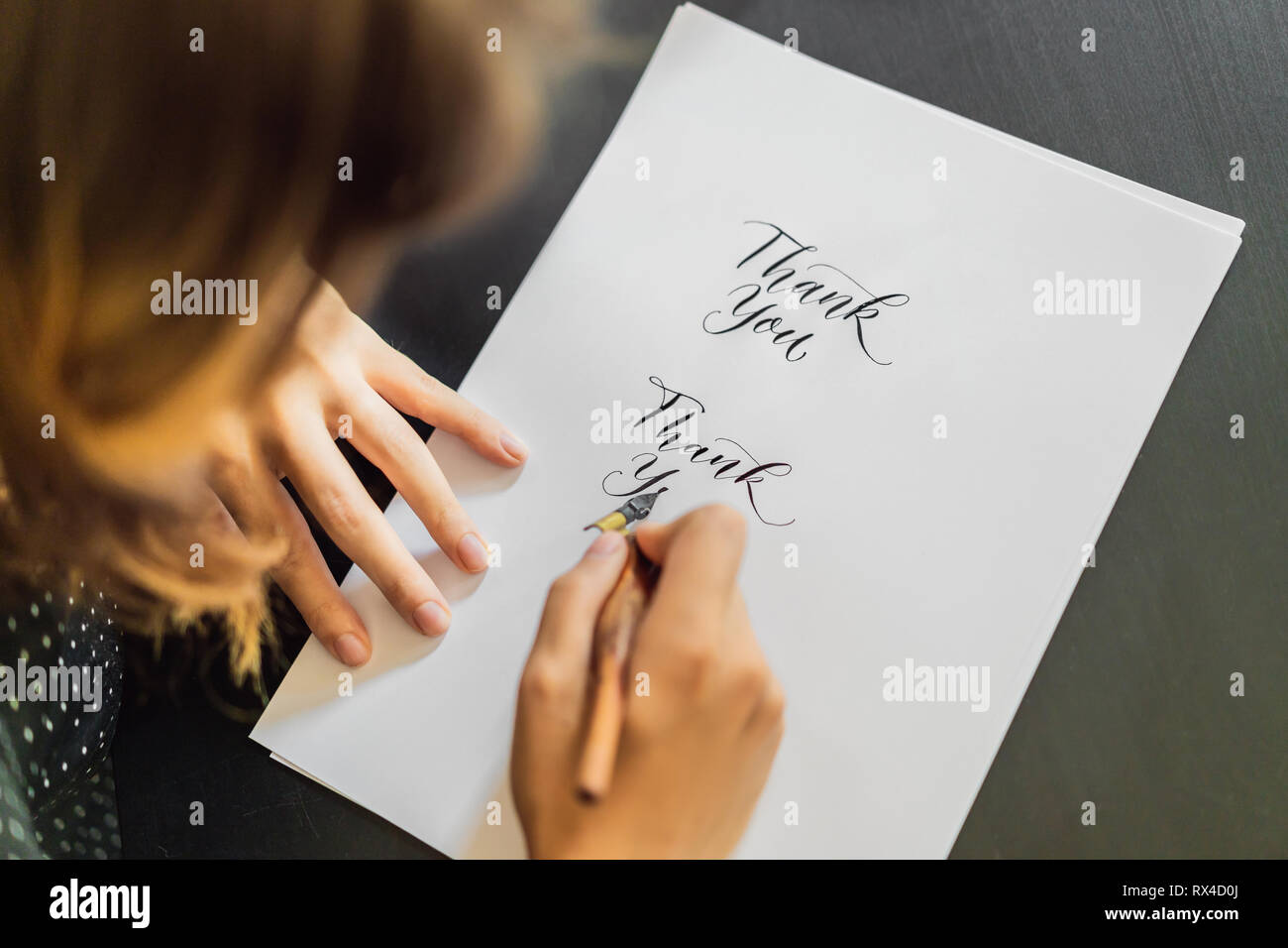 Calligrapher hands writes phrase on white paper. Phrase - Thank you ...