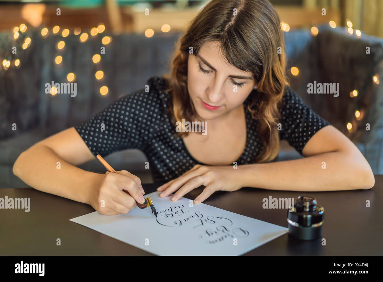 Calligrapher Young Woman writes phrase on white paper. Dream big, set ...
