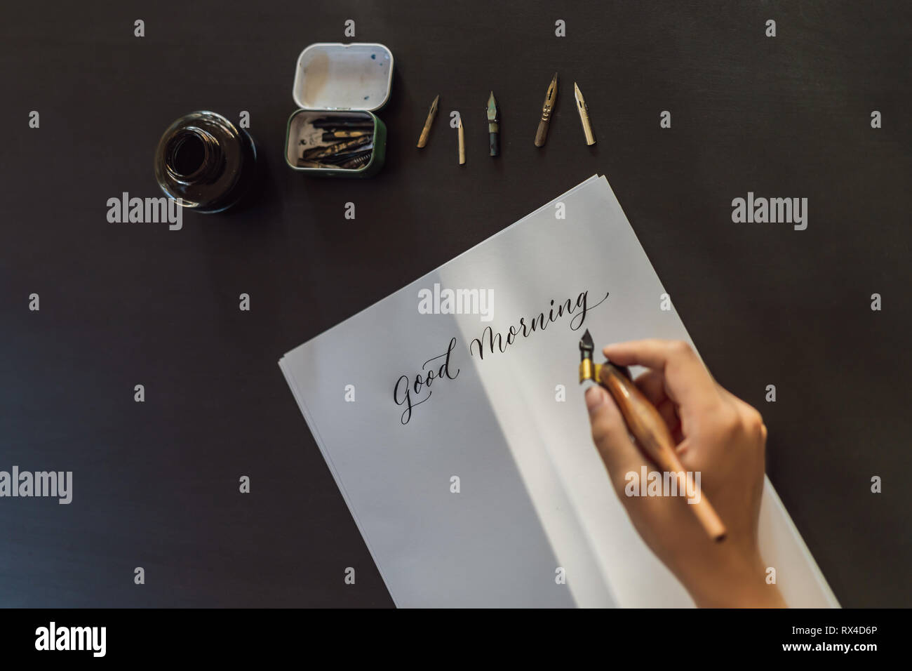 Calligrapher hands writes phrase on white paper. Phrase - Good morning ...