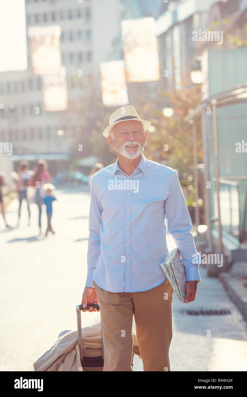 Happy Senior tourist man with suitcase in city Stock Photo - Alamy