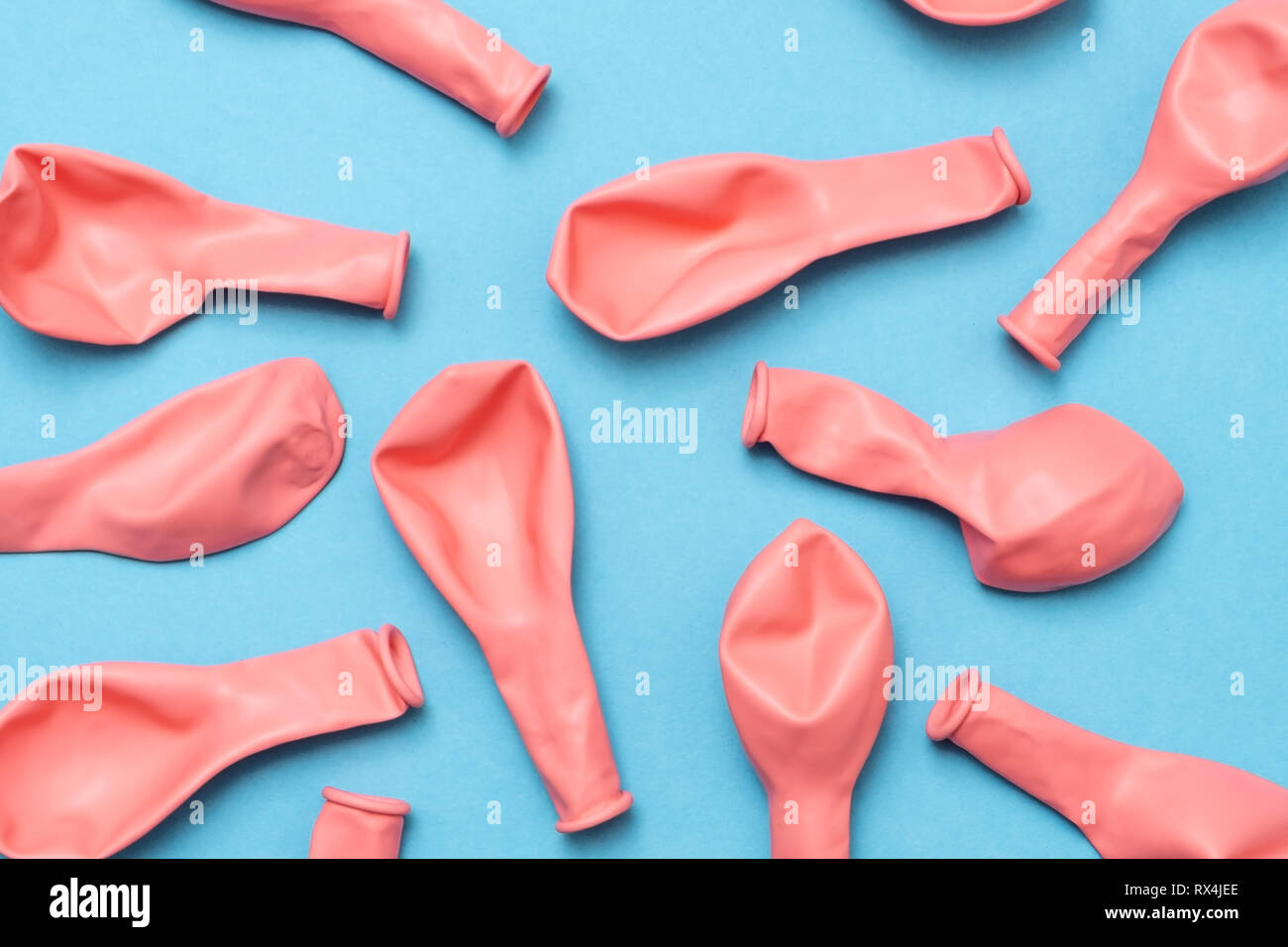 Pink blown off balloons on isolated blue background. Flat lay view ...