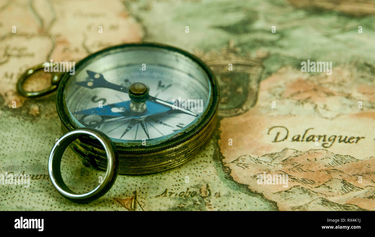 A small compass and a ring on top of a map. The map used for navigation ...