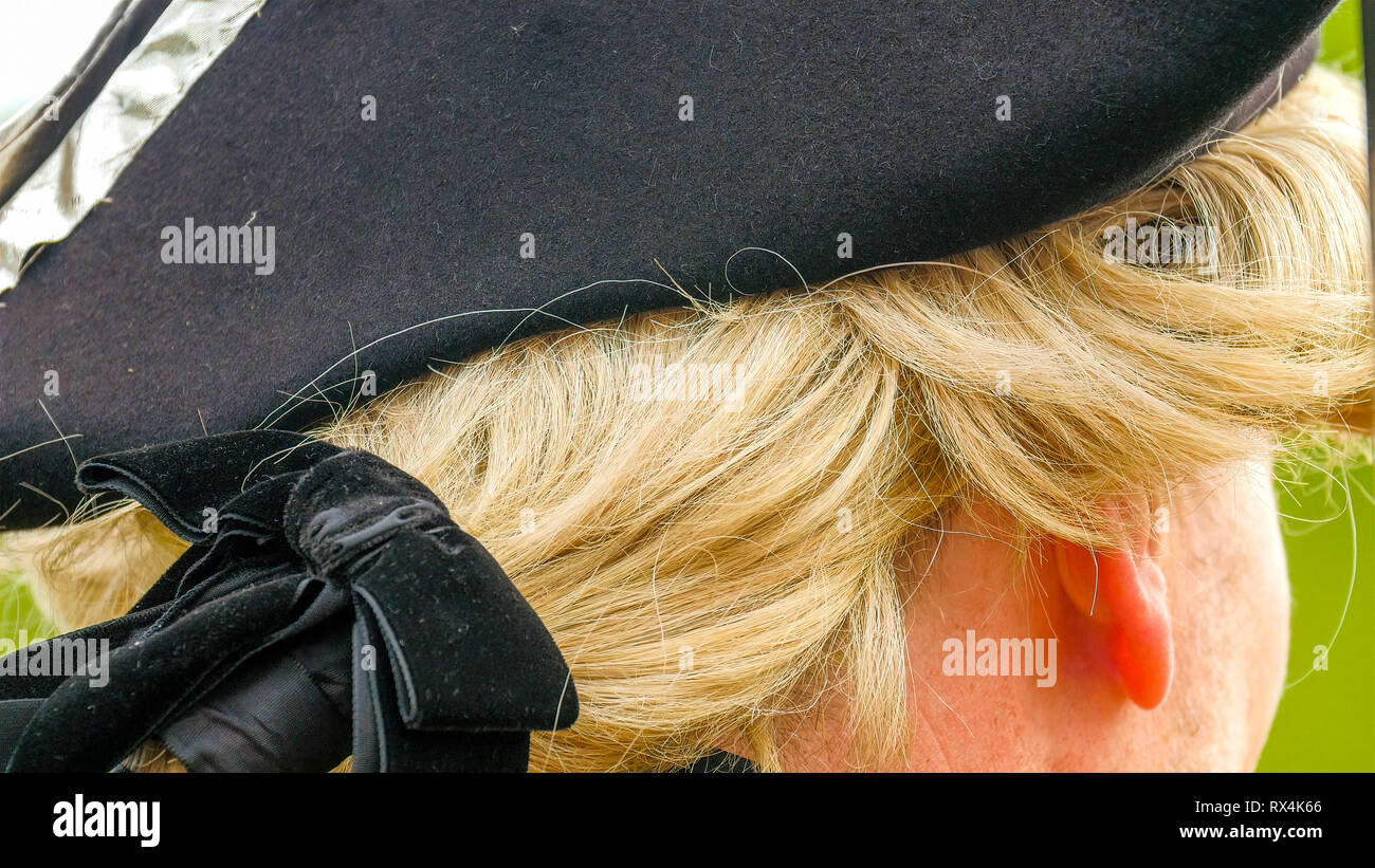The back of the head of the guard. The guard has white hair black cap ...