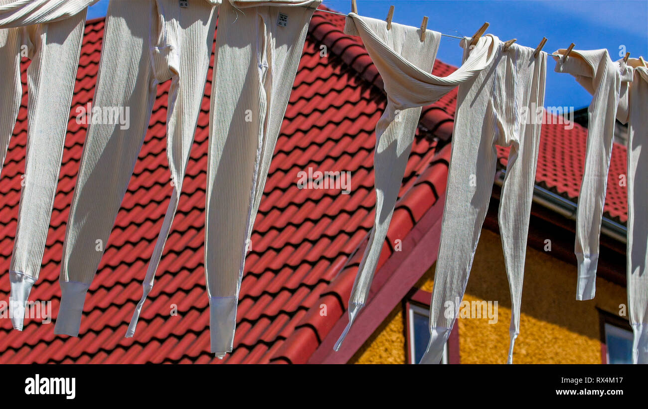 Lots of white clothes hanged on the string. The laundry is being dried ...