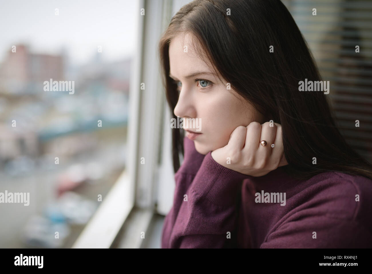 Sad woman looking through the window Stock Photo - Alamy