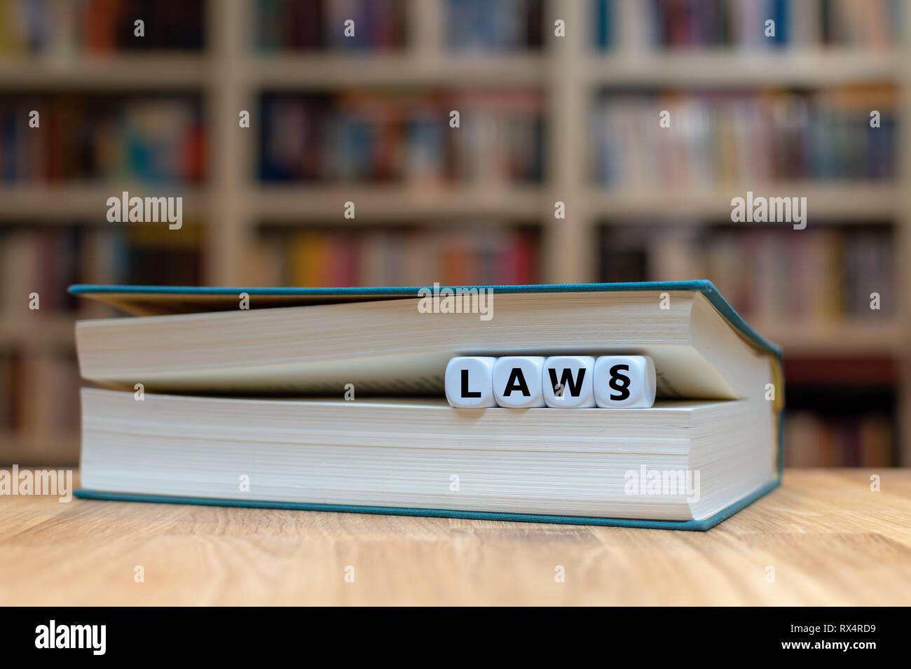 Dice in a book form the word "LAW". Book is lying on a desk in a ...