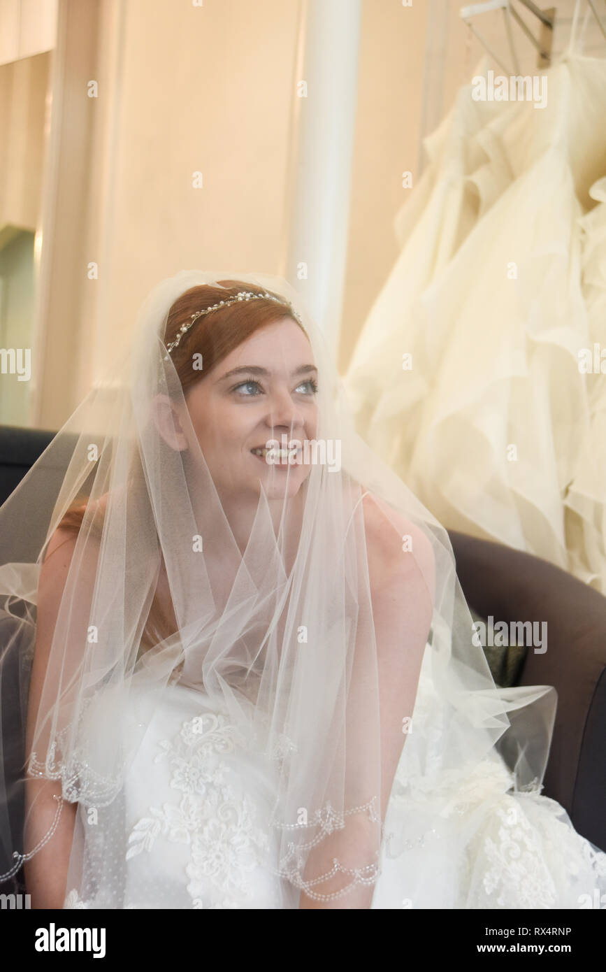A young retty red haired girl tries on Wedding dresses in a Bridal shop ...