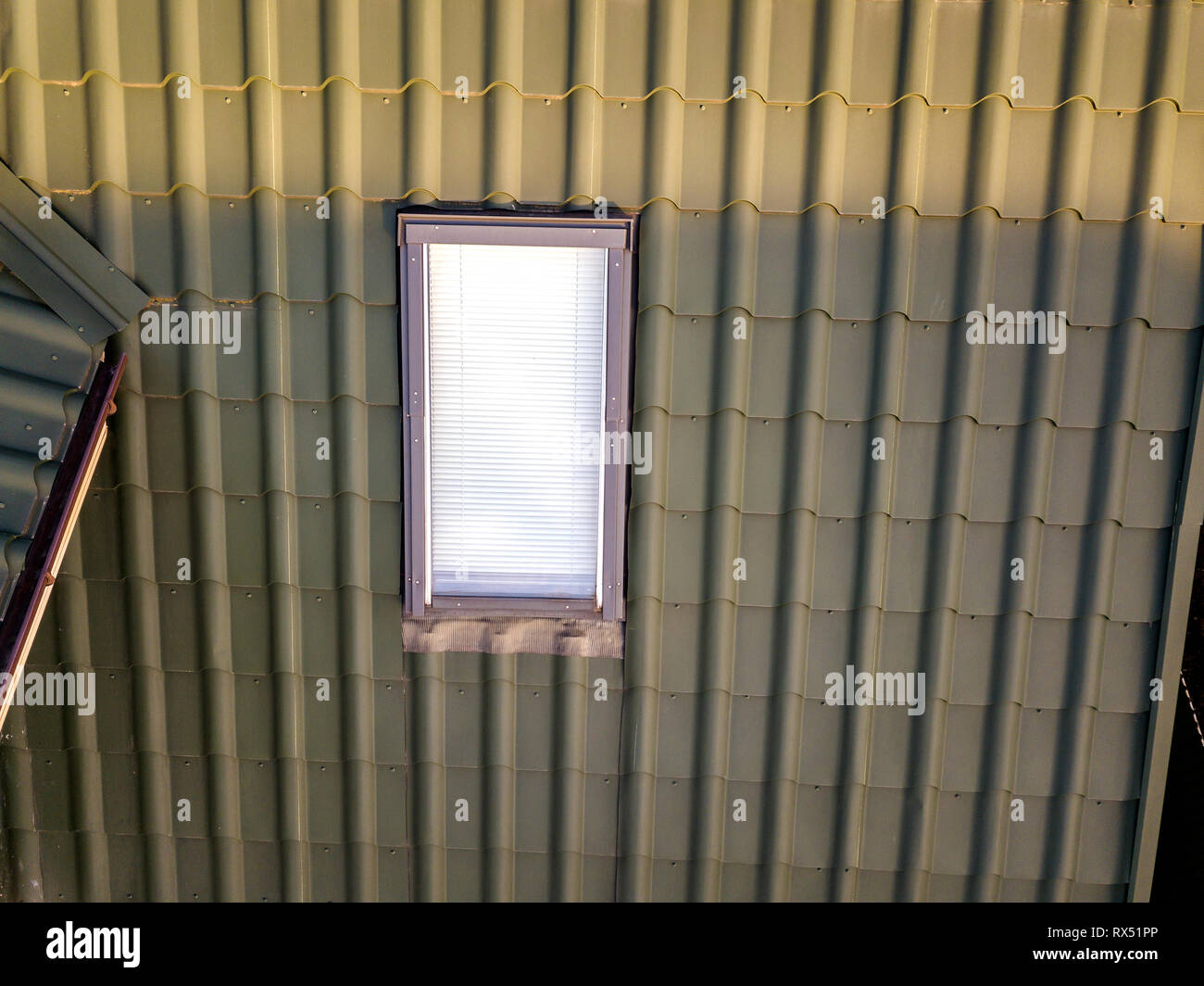 Close-up of new attic plastic window installed in shingled house roof ...