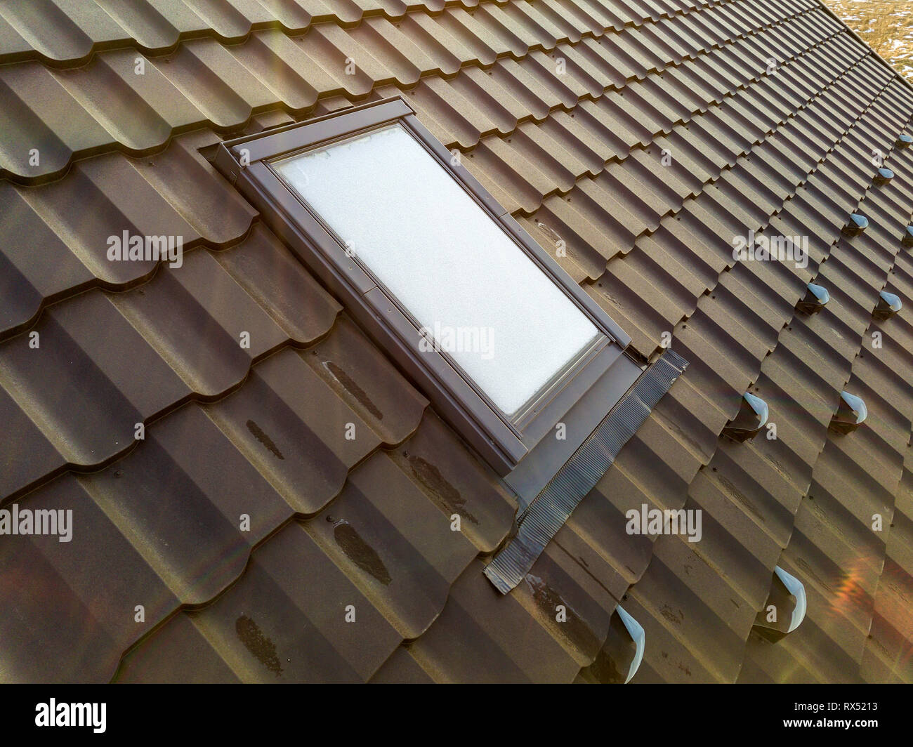 Close-up of new attic plastic window installed in shingled house roof ...