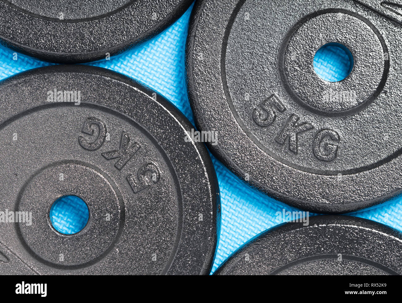 Weight plates on a colourful blue floor inside a weight training gym ...