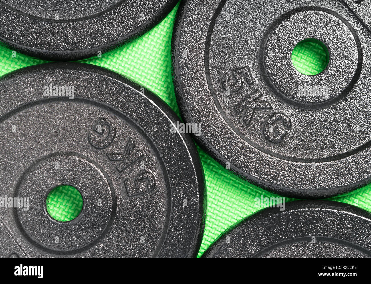 Weight plates on a colourful green floor inside a weight training gym ...