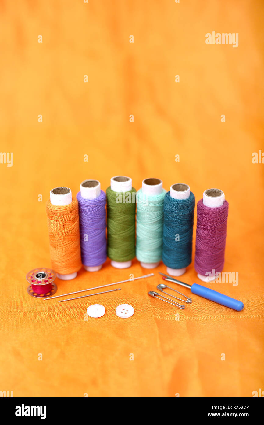 Picture of multicolored sewing thread, needle, bobbin, button, safety ...