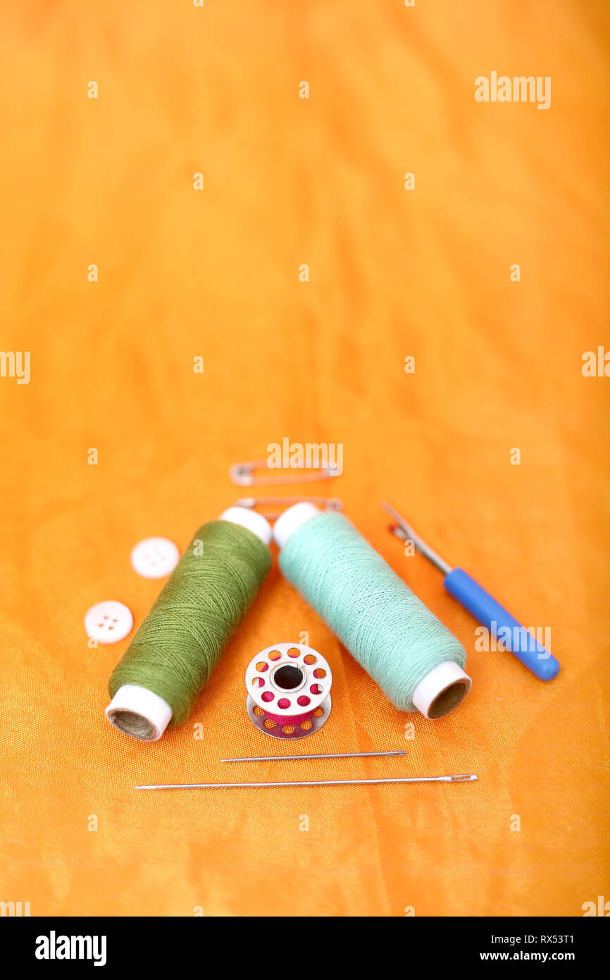 Portrait of sewing thread, needle, bobbin, button, safety pin and ...
