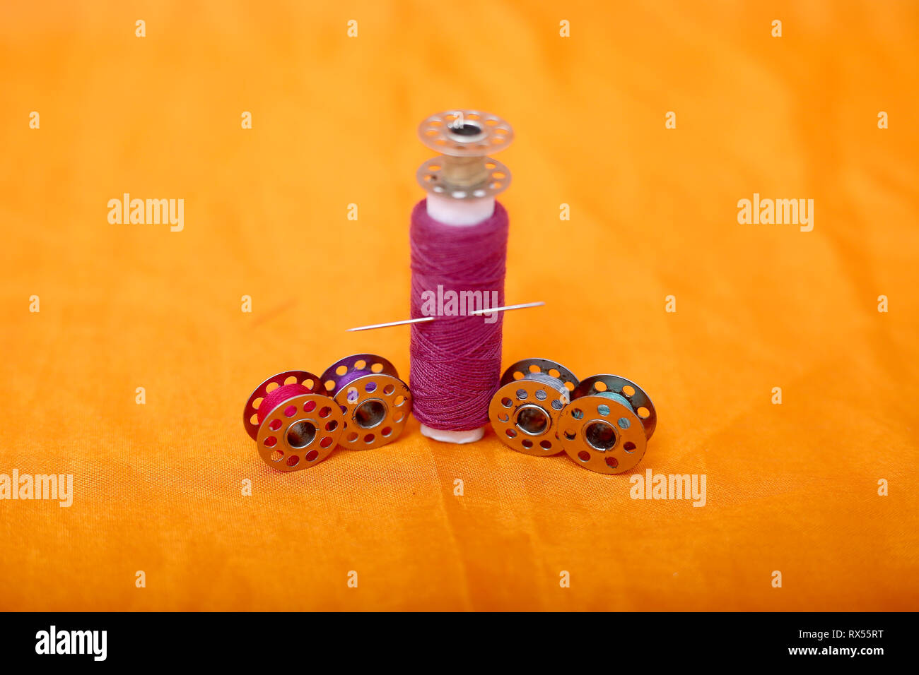 Portrait of one pink sewing thread and bobbins. Isolated on the yellow ...