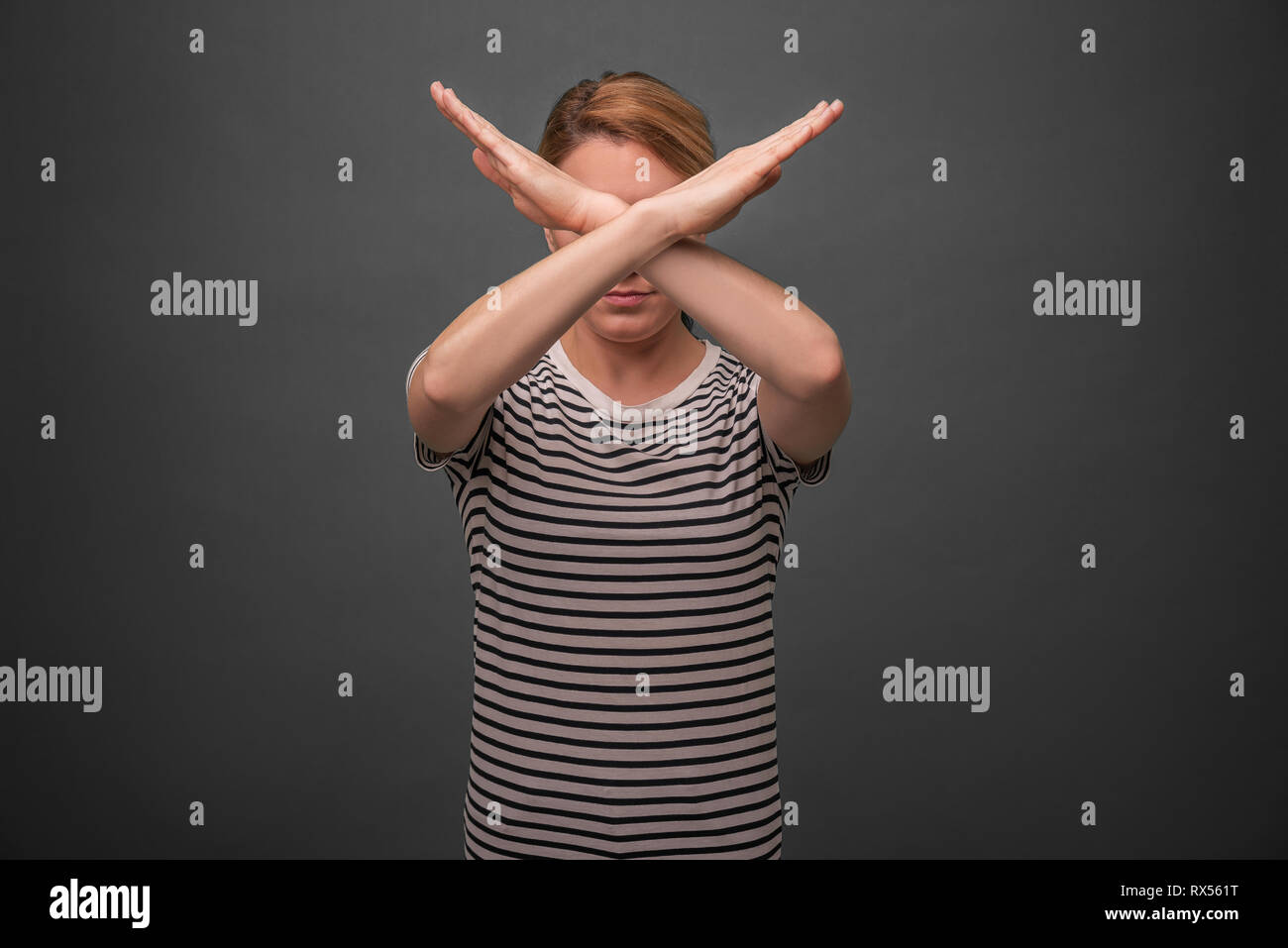 Beautiful woman holding hands cross to cross. Protest or ban. On gray ...