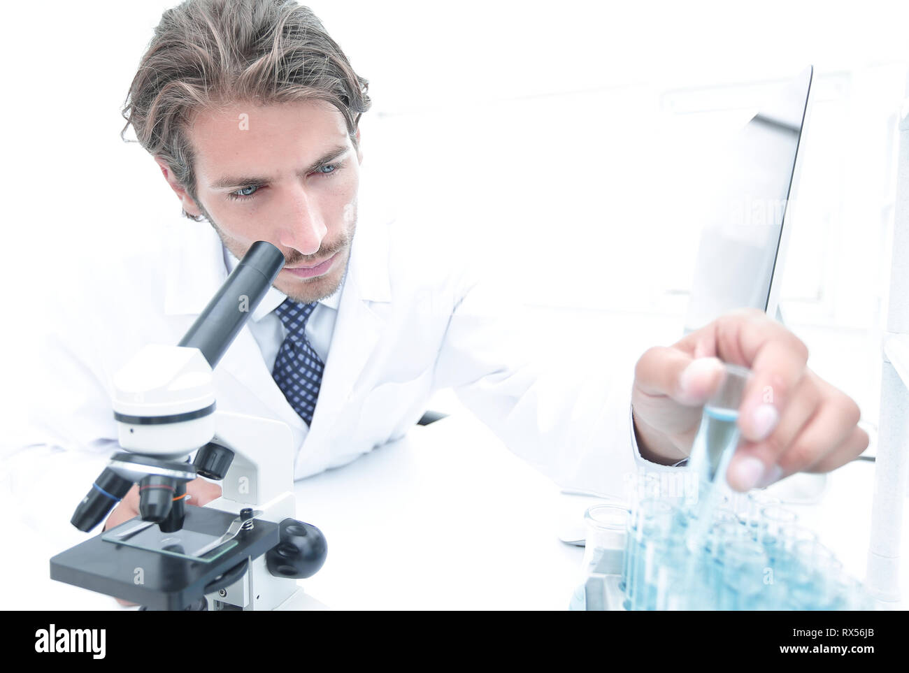 Chemist looking at test-tubes with blue liquids Stock Photo - Alamy