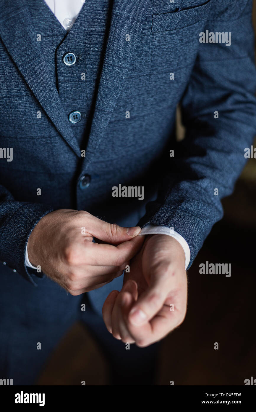 Businessman in a white shirt straightens cuffs, standing at the window ...