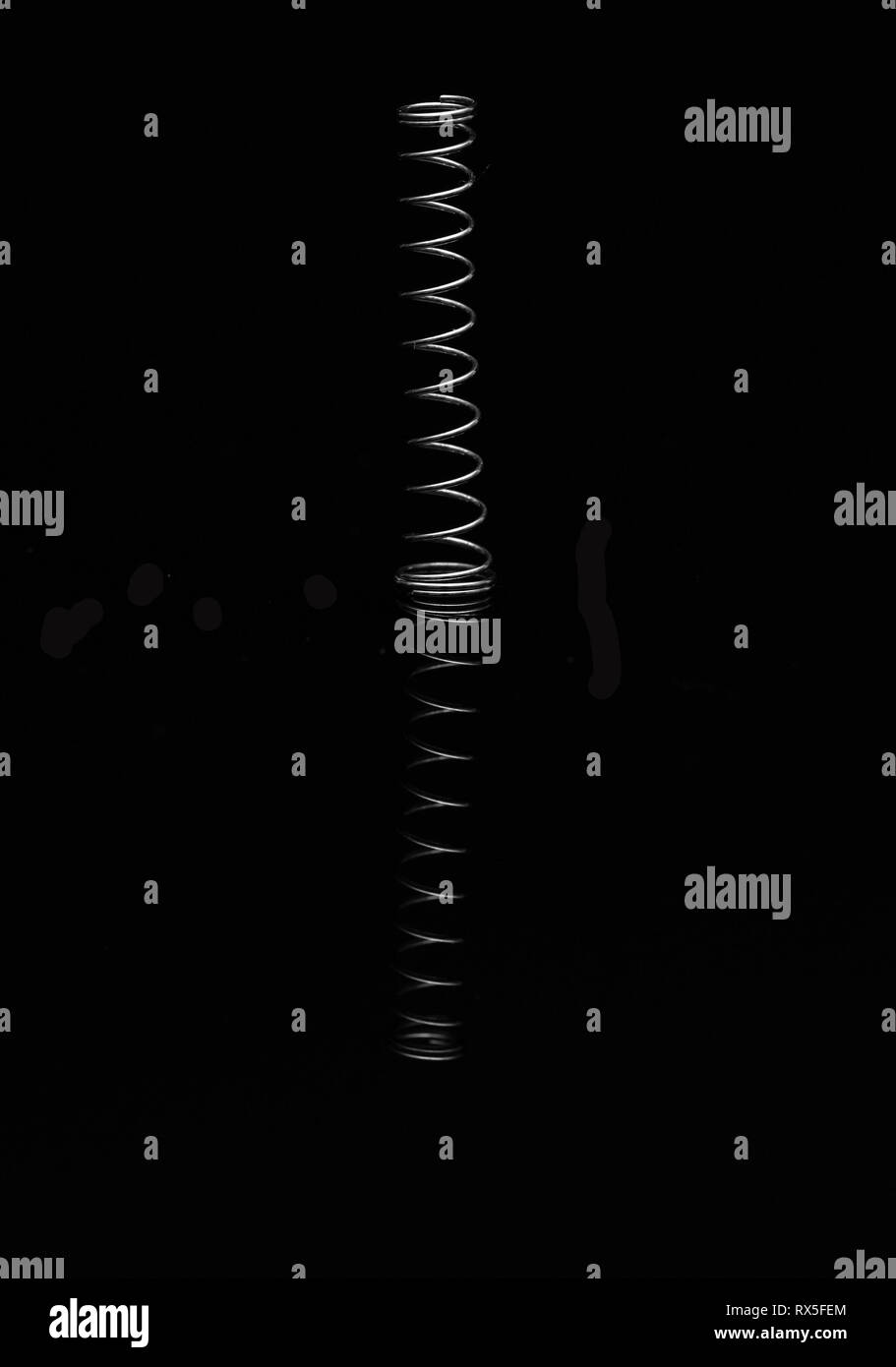 Silver metal spring isolated on black background with mirror reflection ...