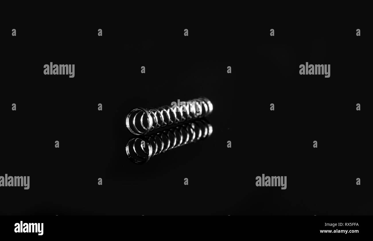 Silver metal spring isolated on black background with mirror reflection ...