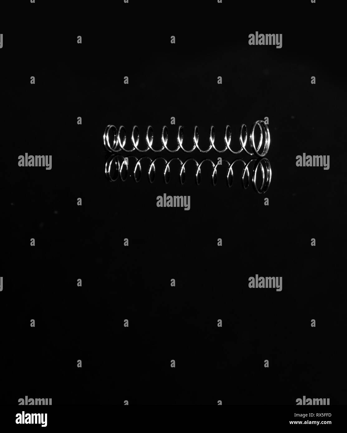 Silver metal spring isolated on black background with mirror reflection ...