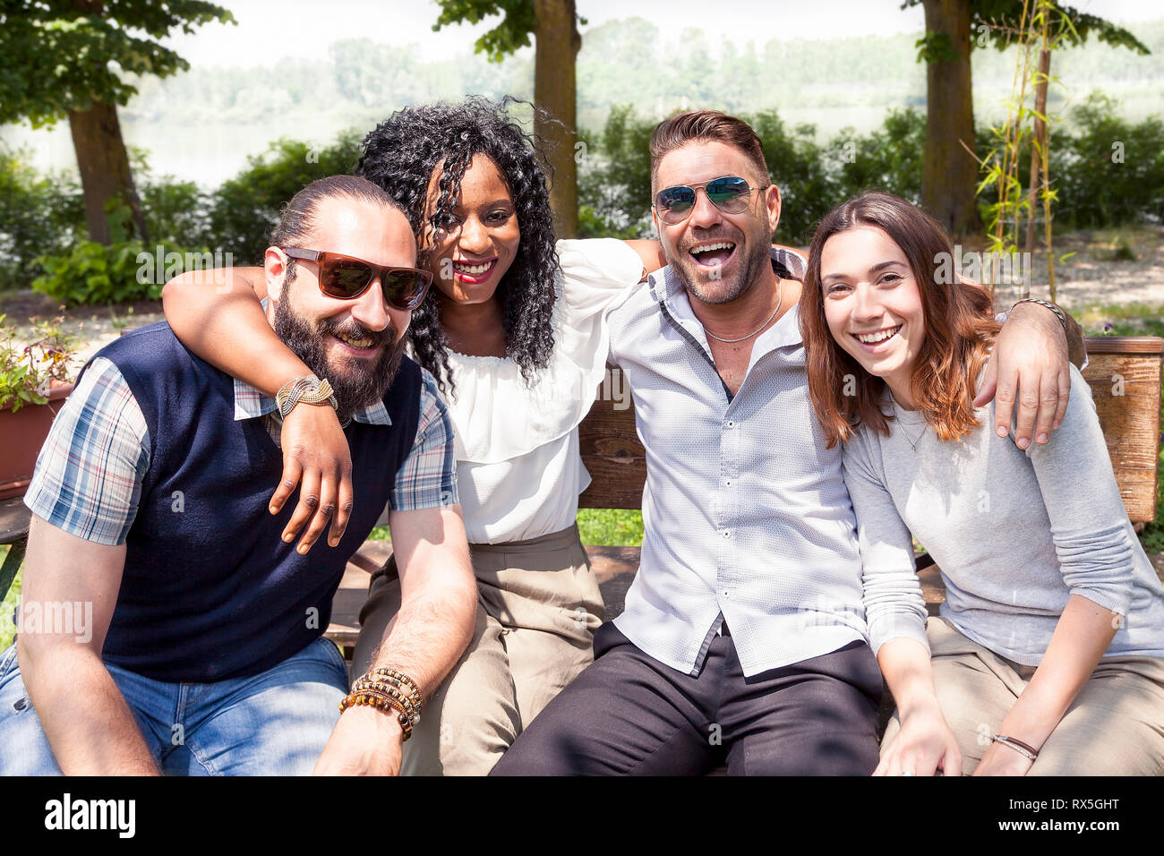 group of young friends have fun sitting on a bench Stock Photo - Alamy