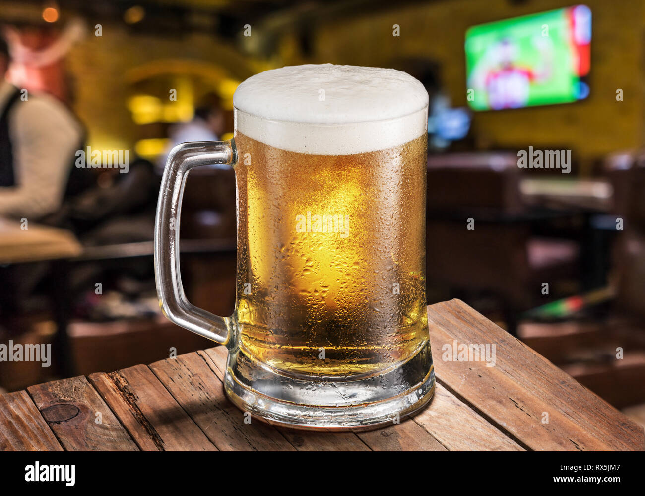 Cold mug of light beer on the bar counter. Pub interior at the ...