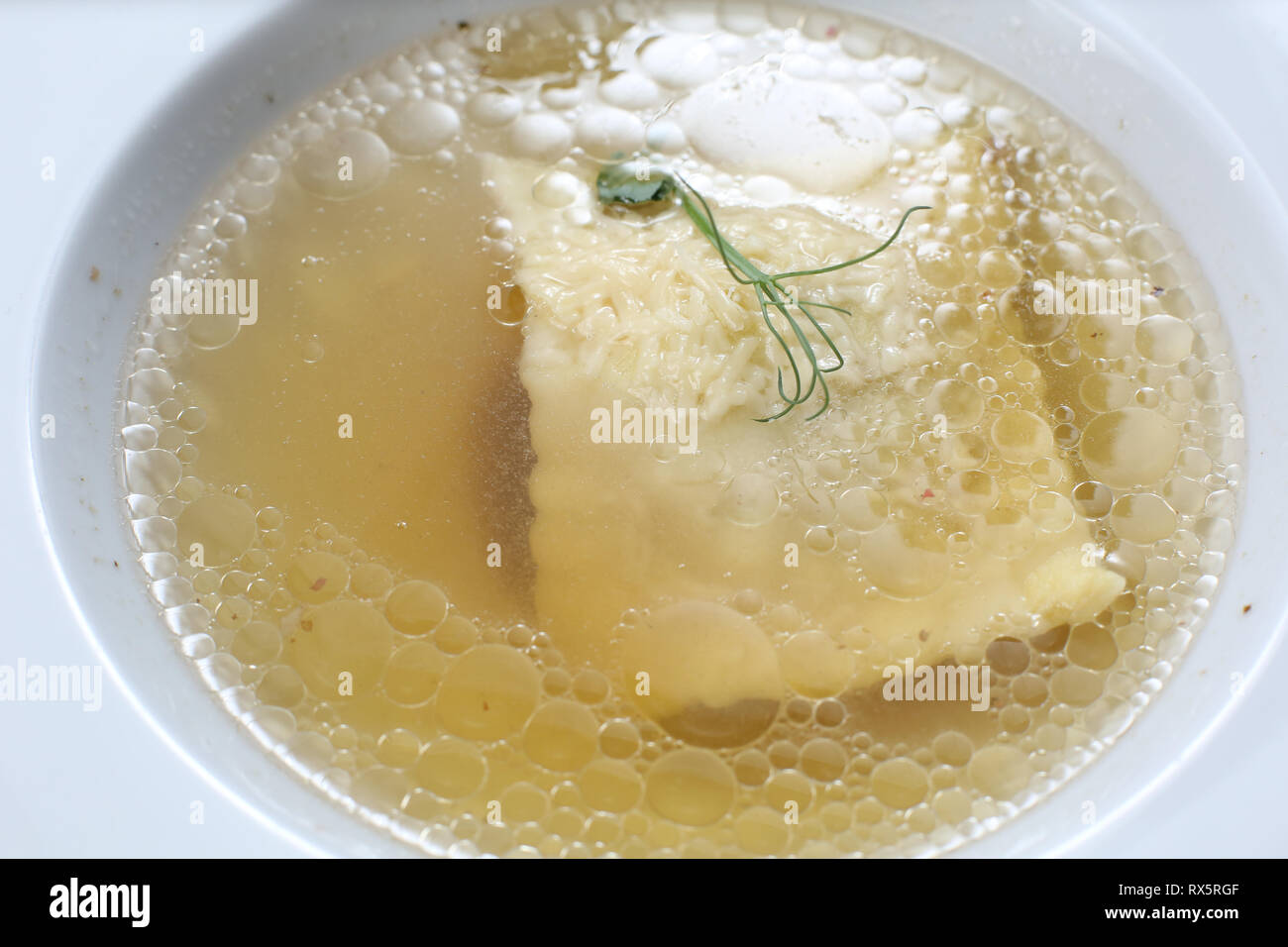 Minimalistic serving of food, white transparent chicken broth in a ...