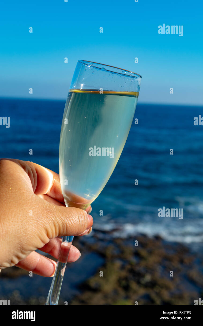 Hand holding glass of Champagne, prosecco or cava, outside terrace with ...