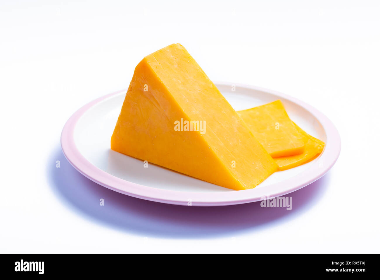 Piece of hard orange Cheddar cheese on white board isolated, close up ...