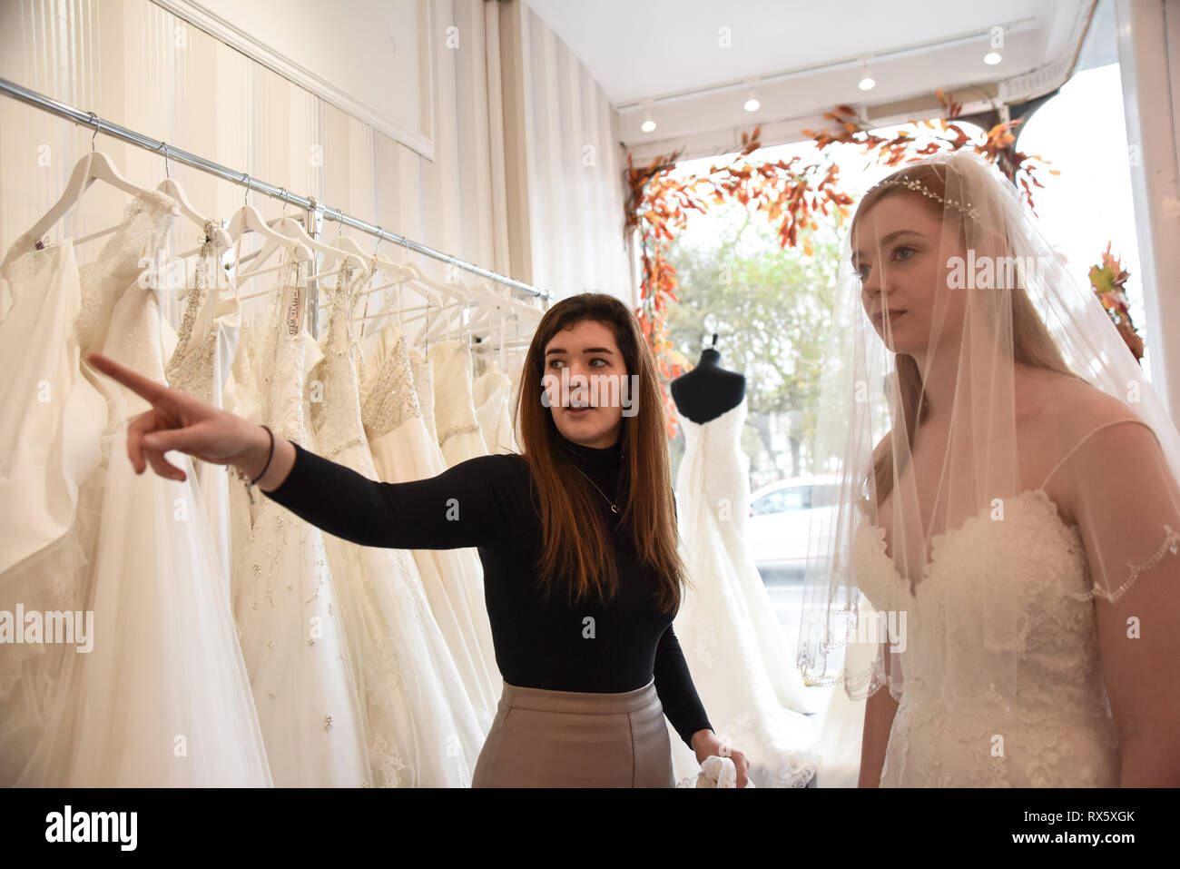 A pretty red haired girl is shopping for a wedding dress in a beautiful ...