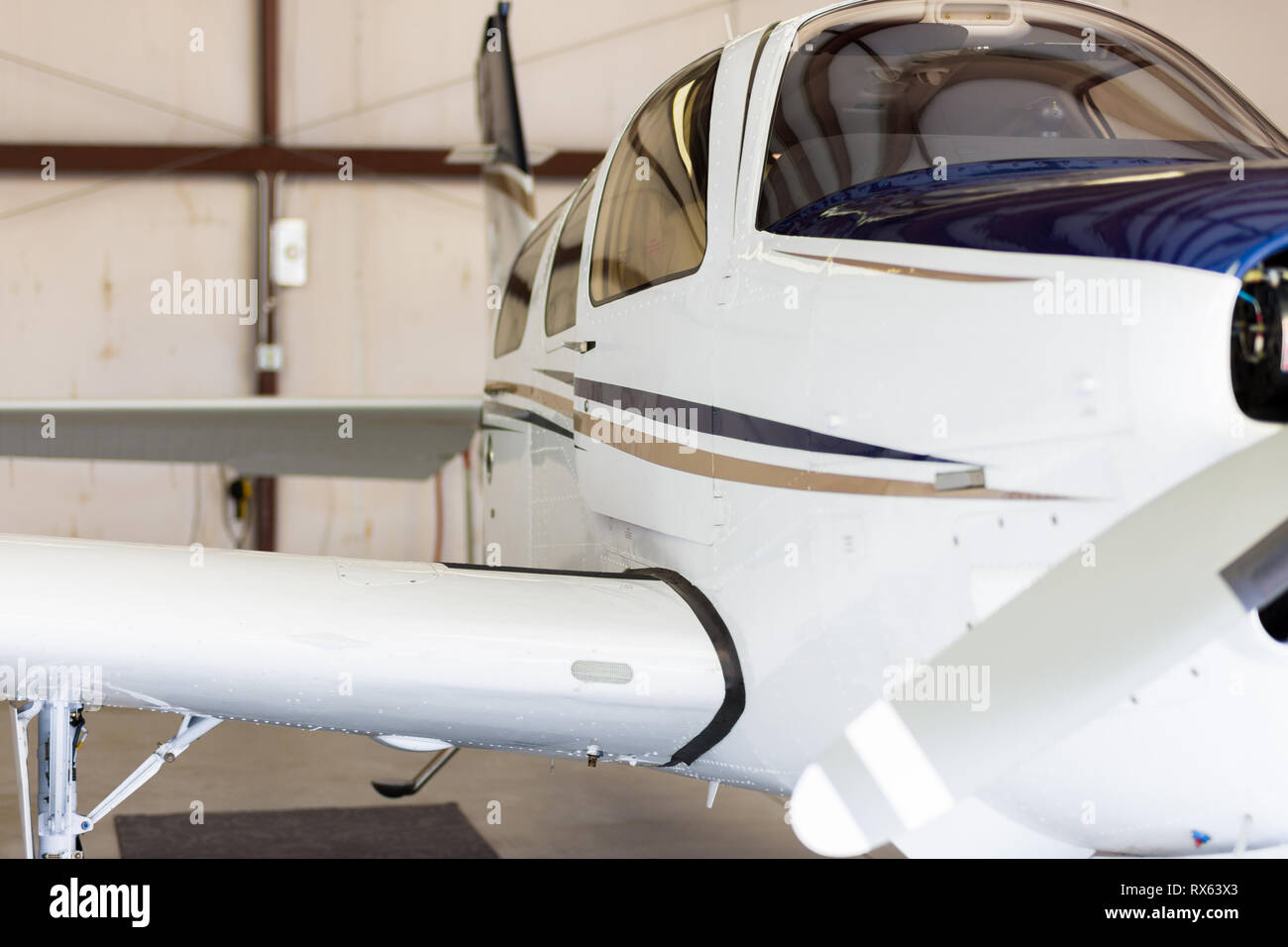 Small white and blue plane in hangar, small cockpit, private, view of ...