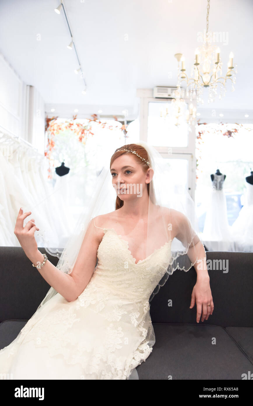 A young retty red haired girl tries on Wedding dresses in a Bridal shop ...