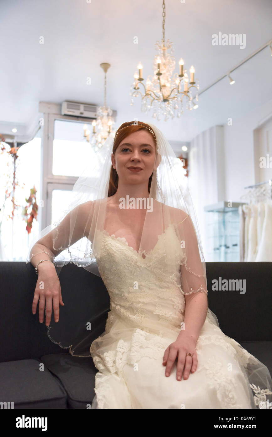A young retty red haired girl tries on Wedding dresses in a Bridal shop ...