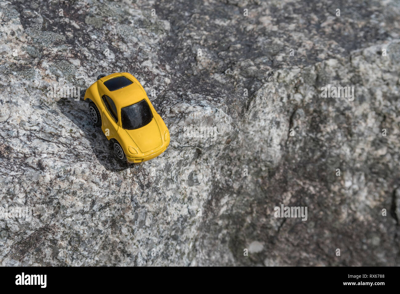 Yellow toy car falling off edge of outcrop. For falling off cliff edge ...