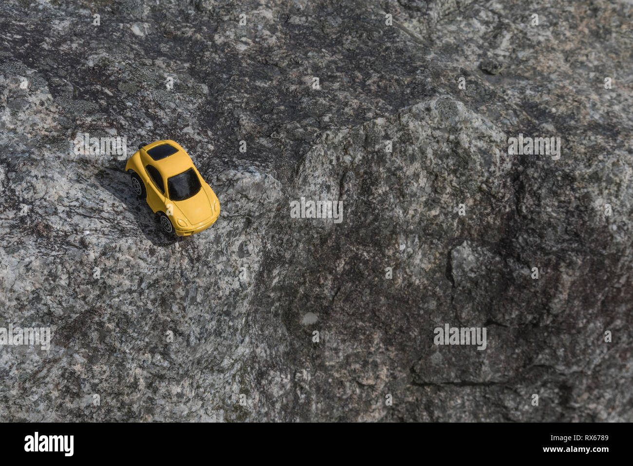 Yellow toy car falling off edge of outcrop. For falling off cliff edge ...