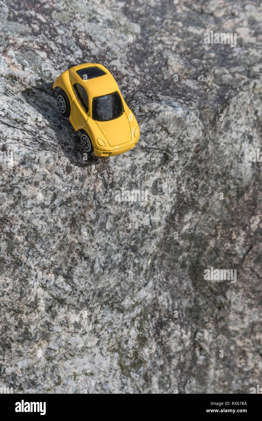 Yellow toy car falling off edge of outcrop. For falling off cliff edge ...