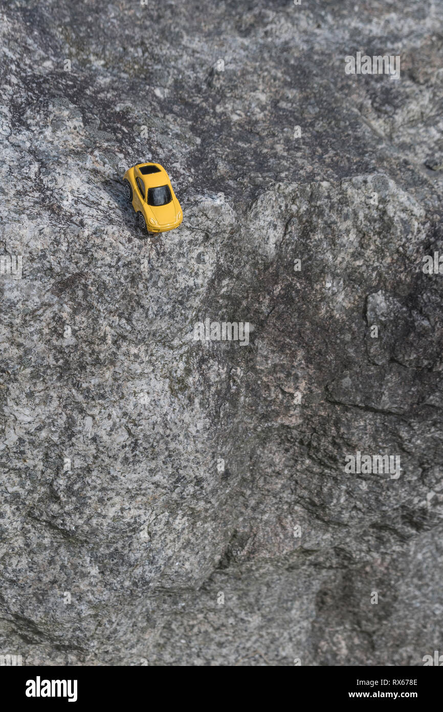 Yellow toy car falling off edge of outcrop. For falling off cliff edge ...