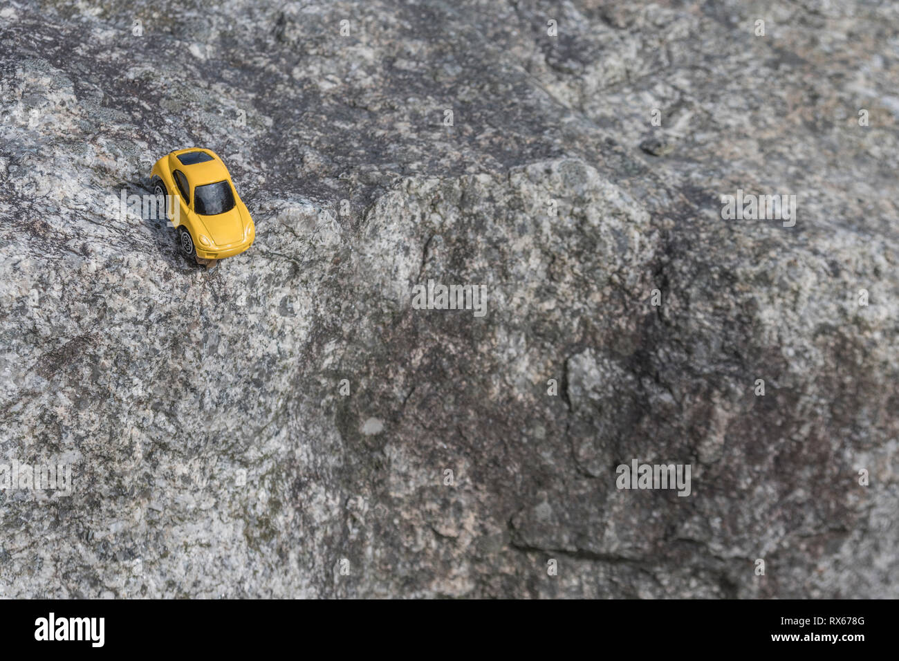 Yellow toy car falling off edge of outcrop. For falling off cliff edge ...