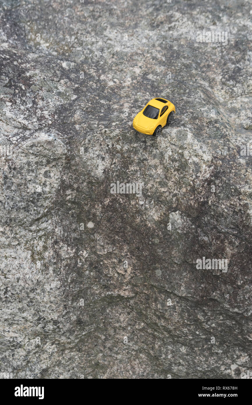 Yellow toy car falling off edge of outcrop. For falling off cliff edge ...