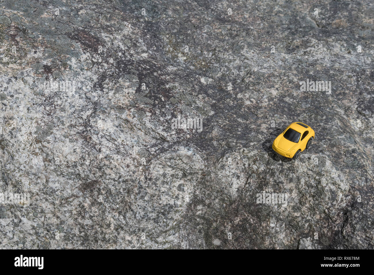 Yellow toy car falling off edge of outcrop. For falling off cliff edge ...