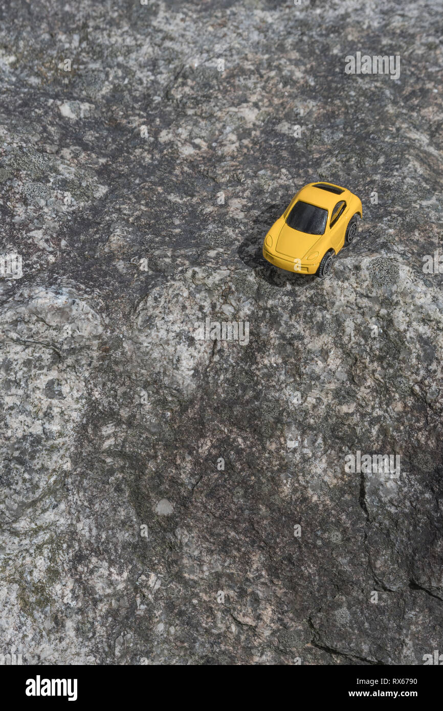 Yellow toy car falling off edge of outcrop. For falling off cliff edge ...