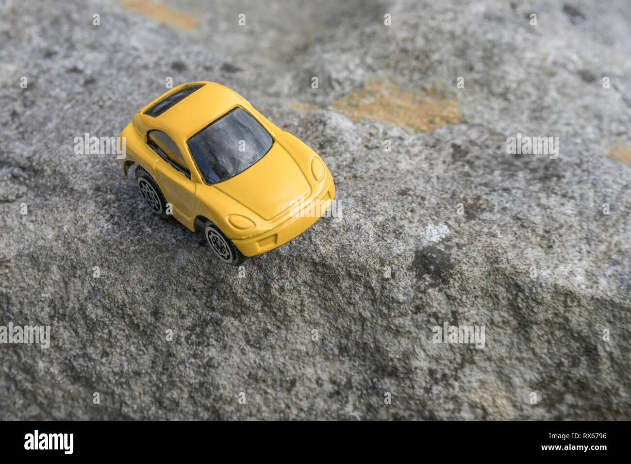 Yellow toy car falling off edge of outcrop. For falling off cliff edge ...