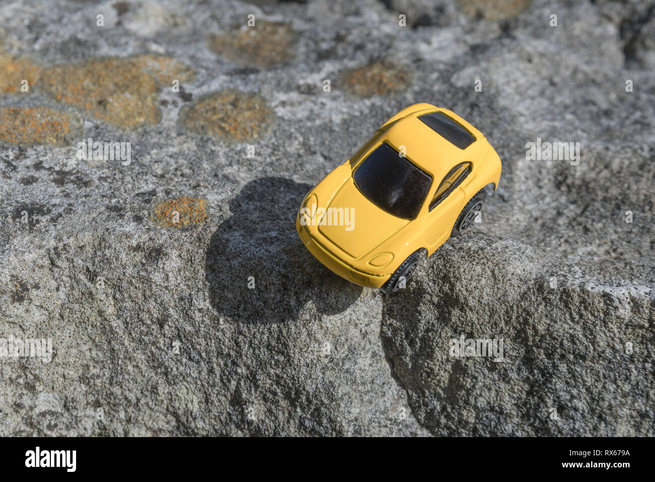 Yellow toy car falling off edge of outcrop. For falling off cliff edge ...