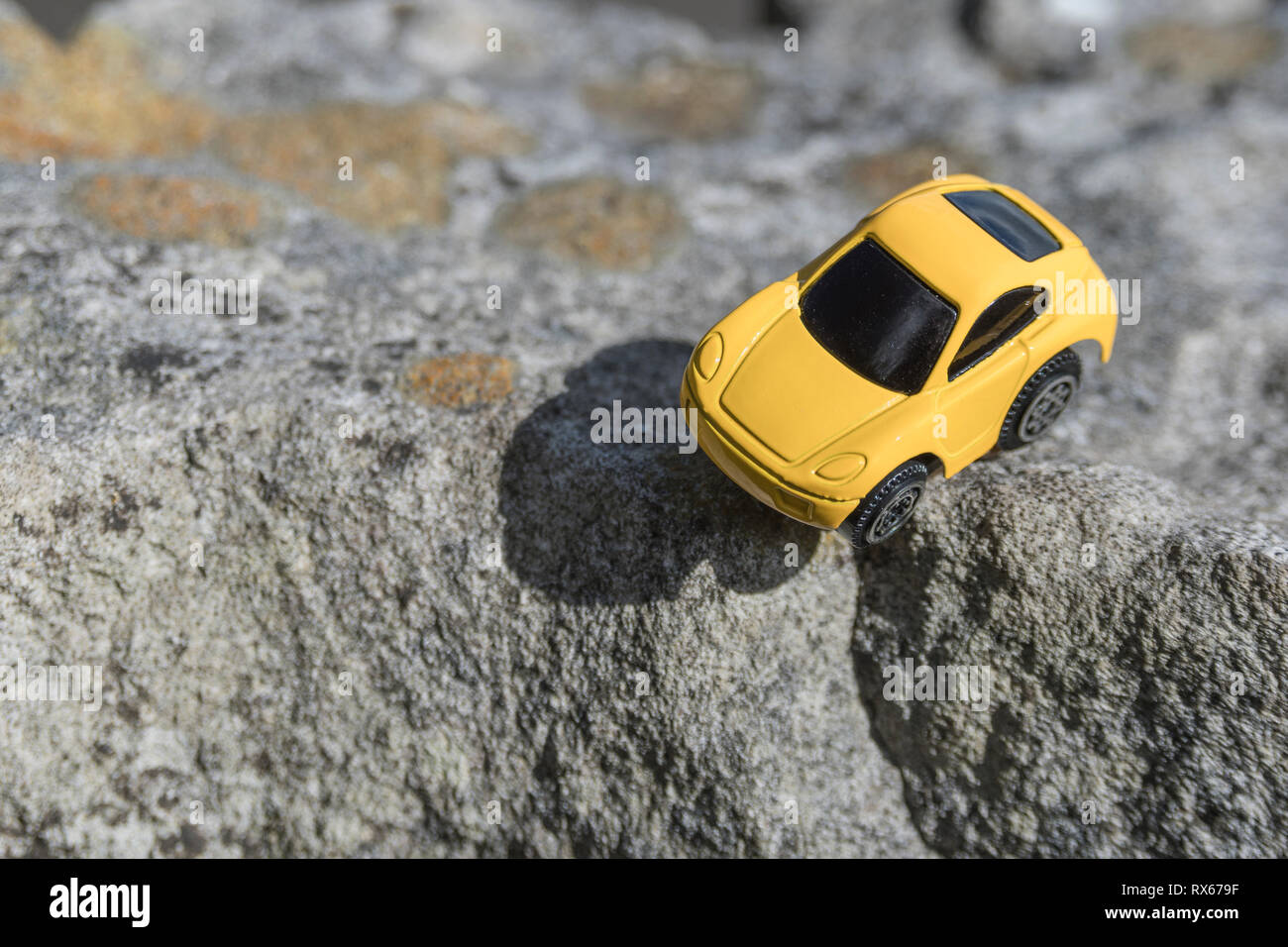 Yellow toy car falling off edge of outcrop. For falling off cliff edge ...