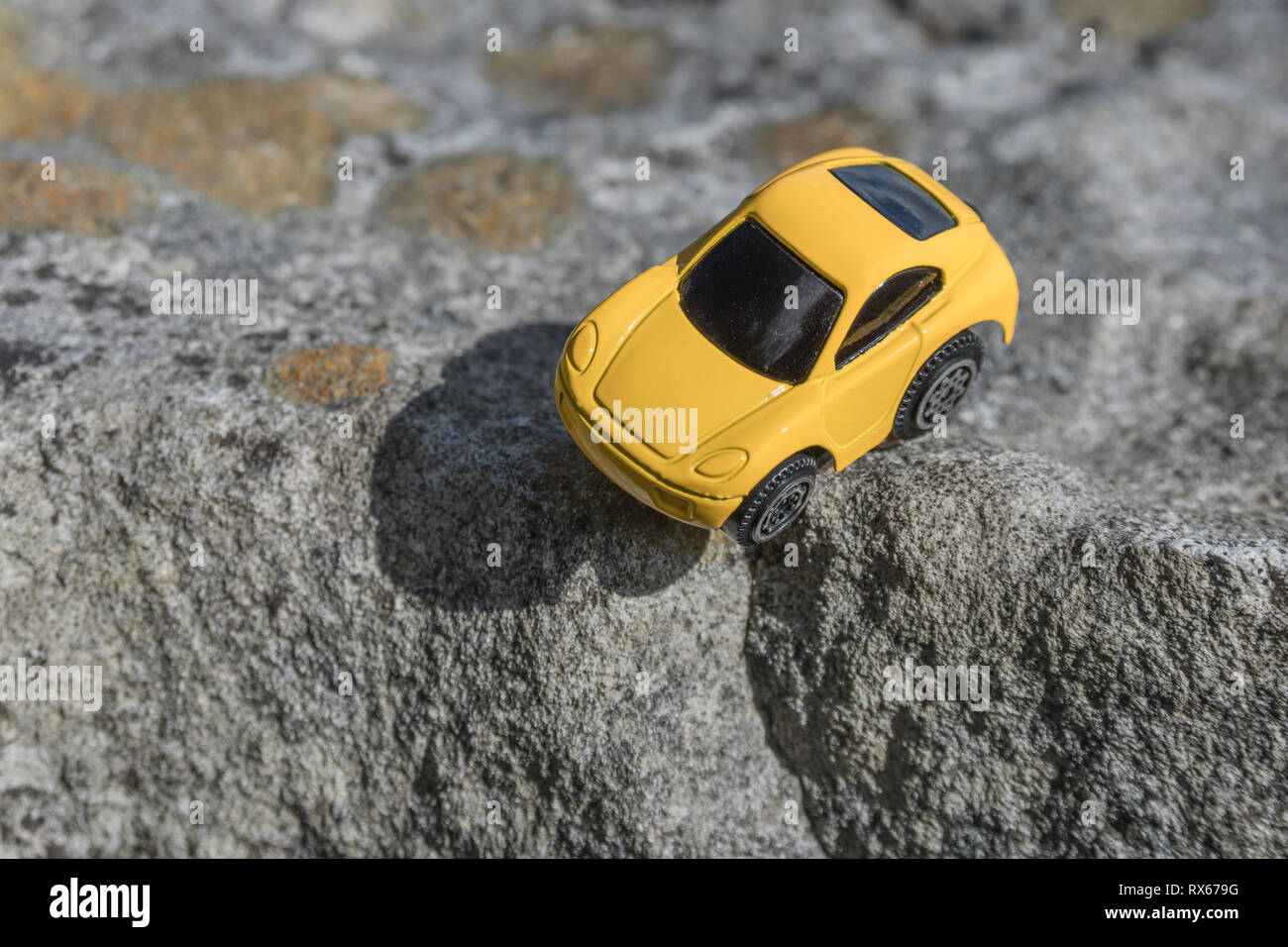 Yellow toy car falling off edge of outcrop. For falling off cliff edge ...