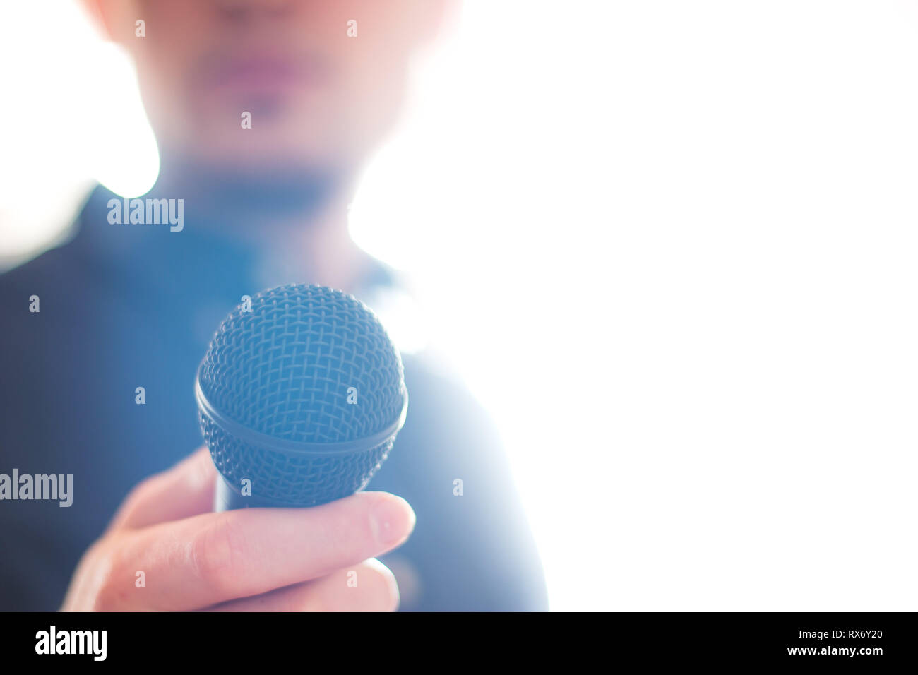 Young man holding a black microphone and speaking into it Stock Photo ...
