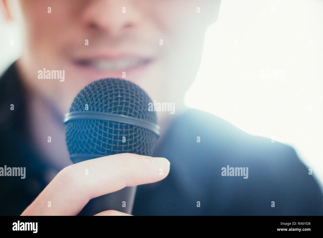 Young man holding a black microphone and speaking into it Stock Photo ...