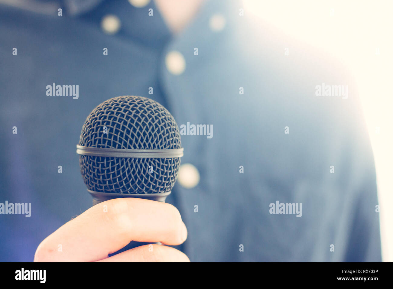 Interview: Black microphone in the foreground, man with blue shirt in ...