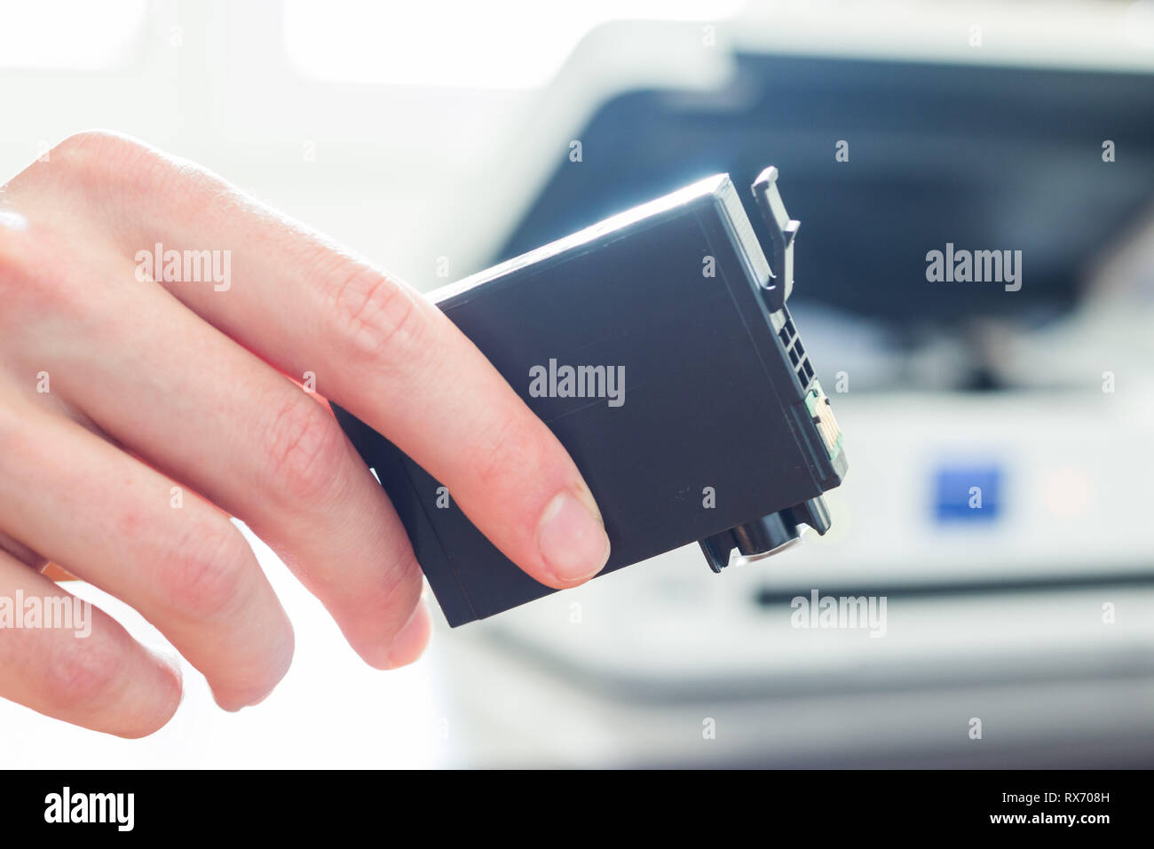 Third party printer cartridge in the hand, printer in the blurry ...