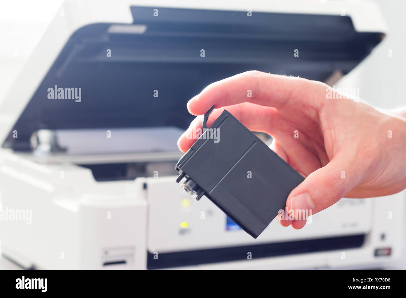 Third party printer cartridge in the hand, printer in the blurry ...